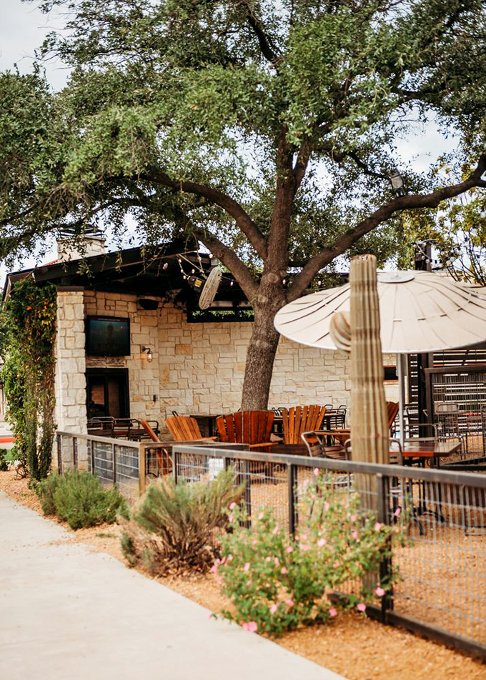 Under the watchful branches of a Texas oak, this outdoor patio invites you to linger over cocktails as the evening softens.