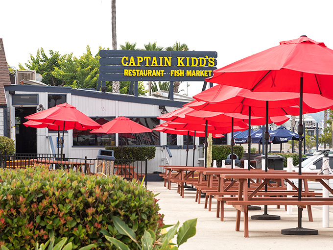 Red umbrellas create an oasis of shade where seafood dreams come true. Those picnic tables have heard more "mmms" than a meditation retreat.