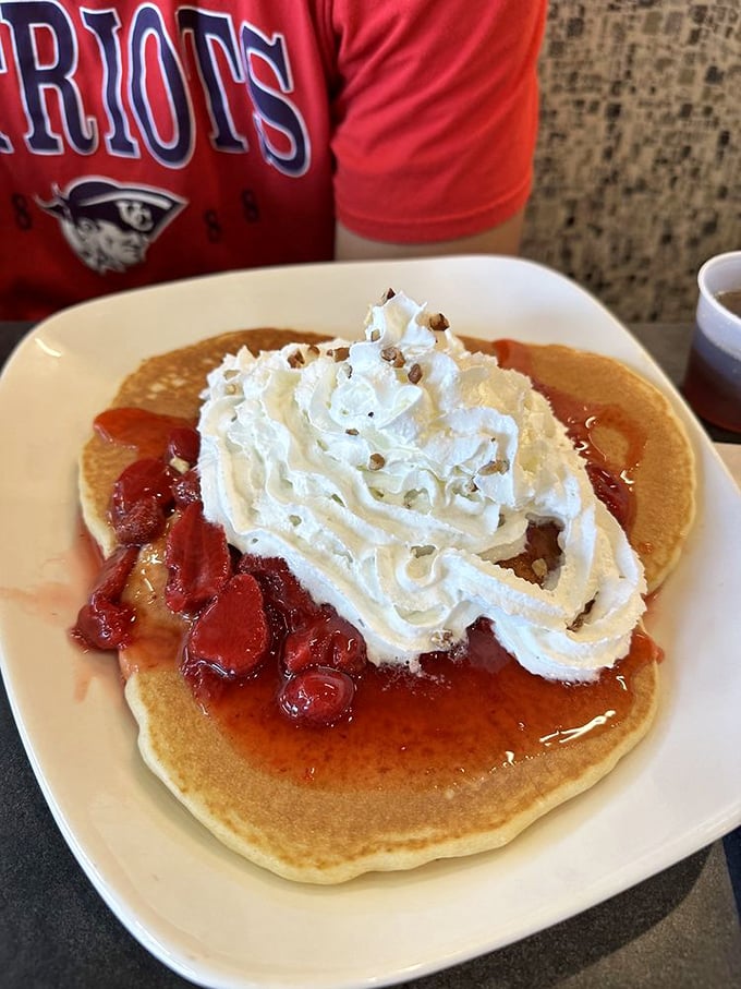 These pancakes don't just come with strawberry topping—they arrive with a crown of whipped cream that demands both respect and immediate consumption.