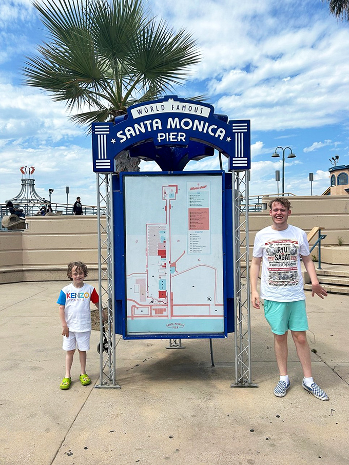 Two visitors flank the official pier guide, their expressions confirming what we all know—some places really do live up to the hype.