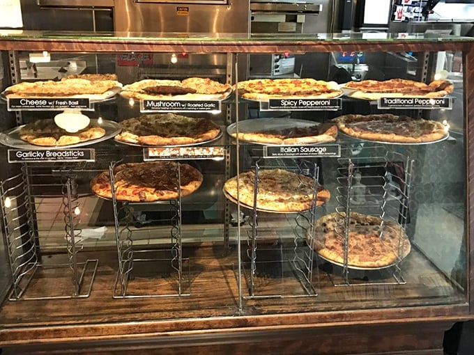 The display case: where pizza dreams are born and diet resolutions go to die. Each pie patiently waits its turn to change someone's day.