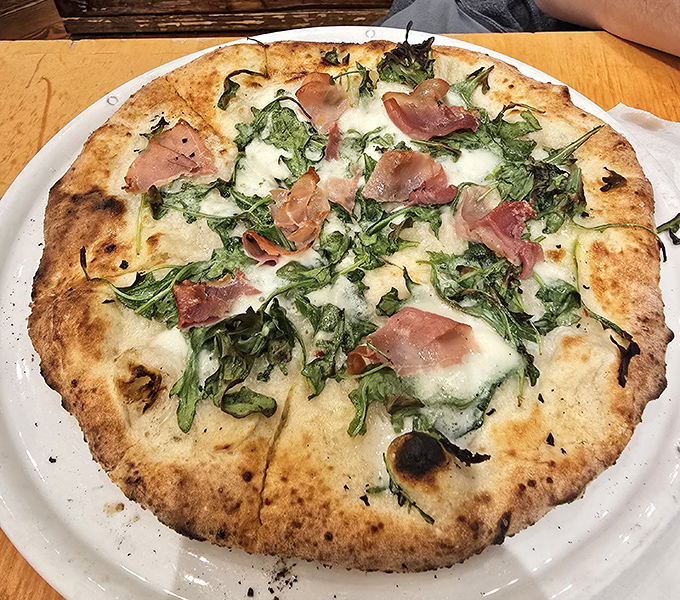 A pizza that defies expectations&mdash;thin crust, prosciutto, and fresh greens creating a harmony that would make even Italian nonnas nod in approval. 