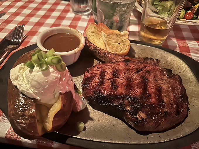 The ribeye arrives like a meaty promise fulfilled&mdash;charred exterior, rosy interior, with a baked potato sidekick that's dressed for the occasion.