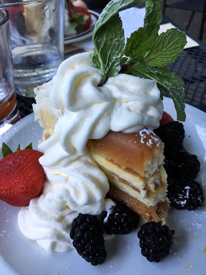A slice of cake that doesn't know the meaning of restraint, topped with a cloud of whipped cream and a mint sprig standing tall like a victory flag.