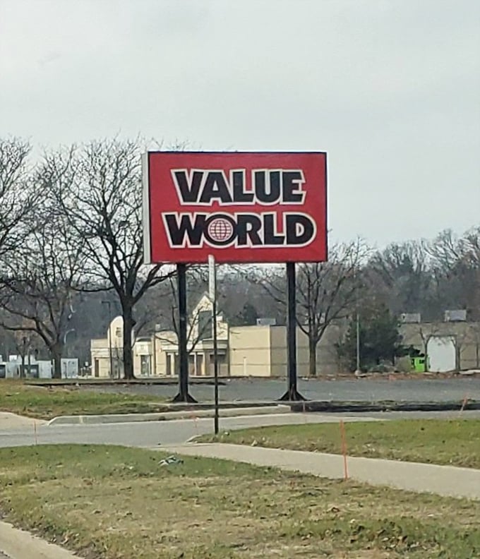 The roadside sign serves as a siren call to budget-conscious shoppers, promising a world of value just off the beaten path.