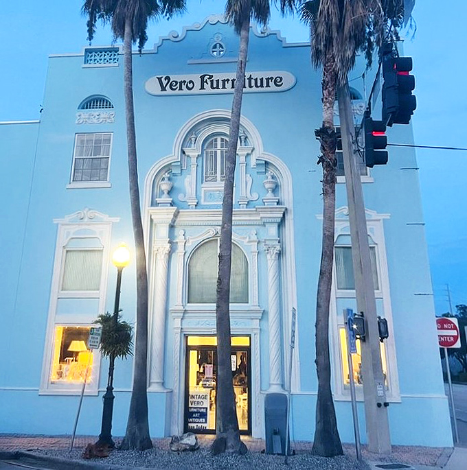As evening falls, the historic fa&ccedil;ade glows with invitation, palm trees standing sentinel over decades of design history waiting inside.