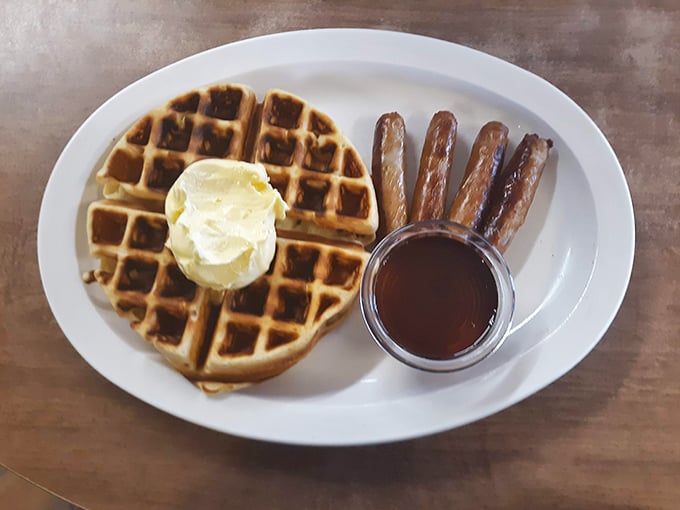 A golden waffle with a perfect butter crown and sausage sentries standing guard&mdash;breakfast royalty that costs less than your fancy coffee drink.
