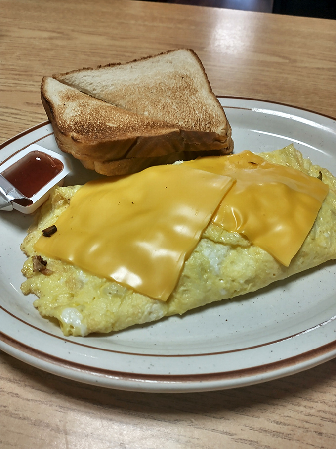 That omelet isn't just folded – it's lovingly embraced by cheese that's melted to the perfect consistency that food scientists have tried and failed to replicate.