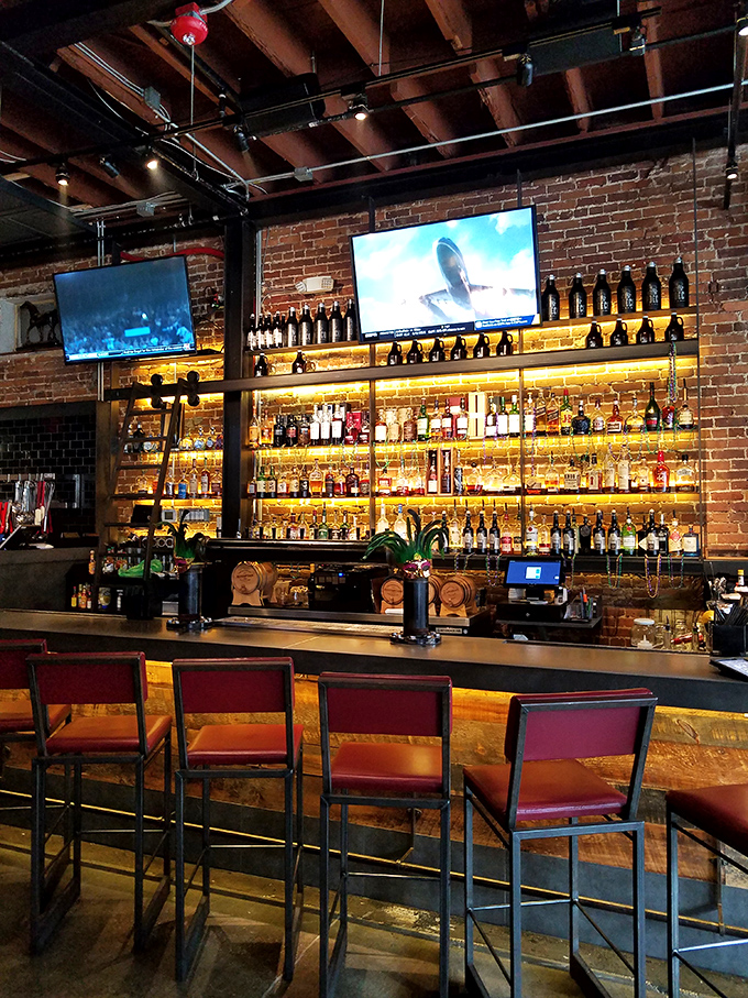 A bar that takes its bourbon seriously, with bottles glowing like amber treasures. This isn't just a drink selection&mdash;it's a whiskey library waiting to be explored.