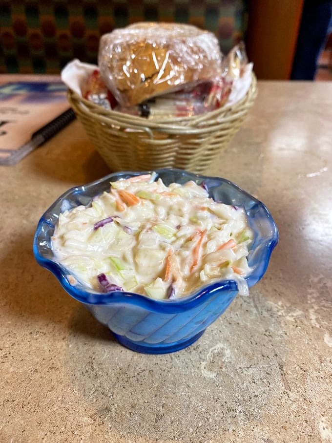 Cole slaw in its natural habitat&mdash;the blue scalloped bowl. This creamy, crunchy side dish patiently waits its turn while bread basket contents mysteriously disappear.