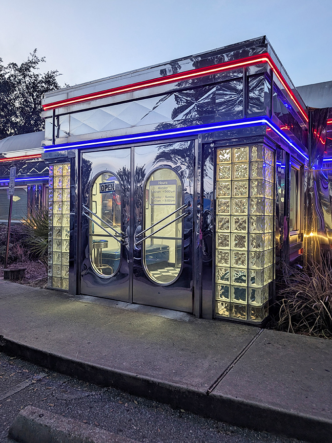 The entrance glows with neon promise as evening falls, glass bricks framing doorways that have welcomed hungry Pensacolians for generations.