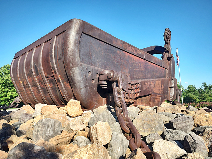 The bucket's weathered profile against blue skies offers a perfect metaphor for American industry—imposing, slightly battered, but undeniably impressive.