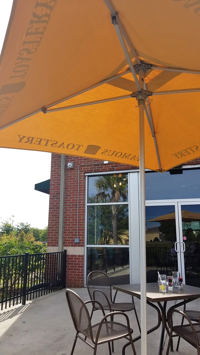 Outdoor seating under Famous Toastery's signature orange umbrellas&mdash;where breakfast meets fresh air and palm trees provide the perfect Carolina backdrop.