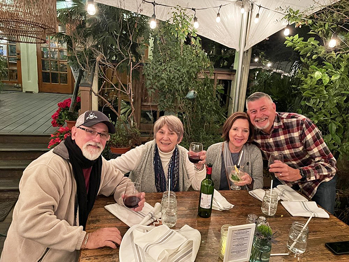 Happy diners raising glasses in the outdoor garden&mdash;because the only thing better than amazing food is sharing it with good company.