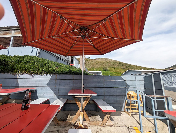 Red picnic tables under striped umbrellas create the perfect oceanside dining room, where million-dollar views come complimentary with your meal.