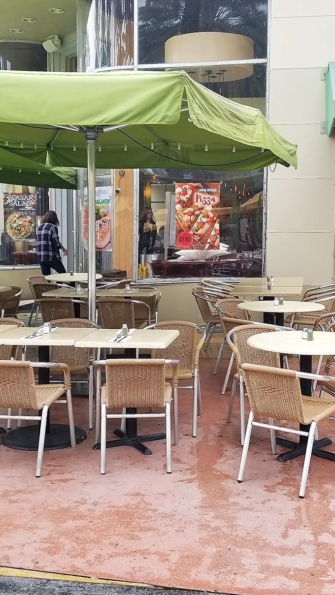 The outdoor seating area offers a quintessential Miami moment – sipping something cold under green umbrellas while watching the world drift by.
