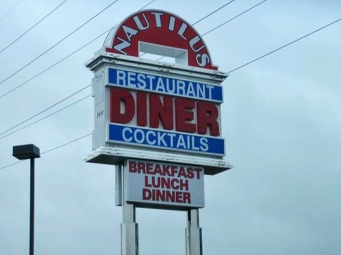 The roadside sign stands tall like a lighthouse for hungry travelers, its red letters spelling relief for empty stomachs miles away.