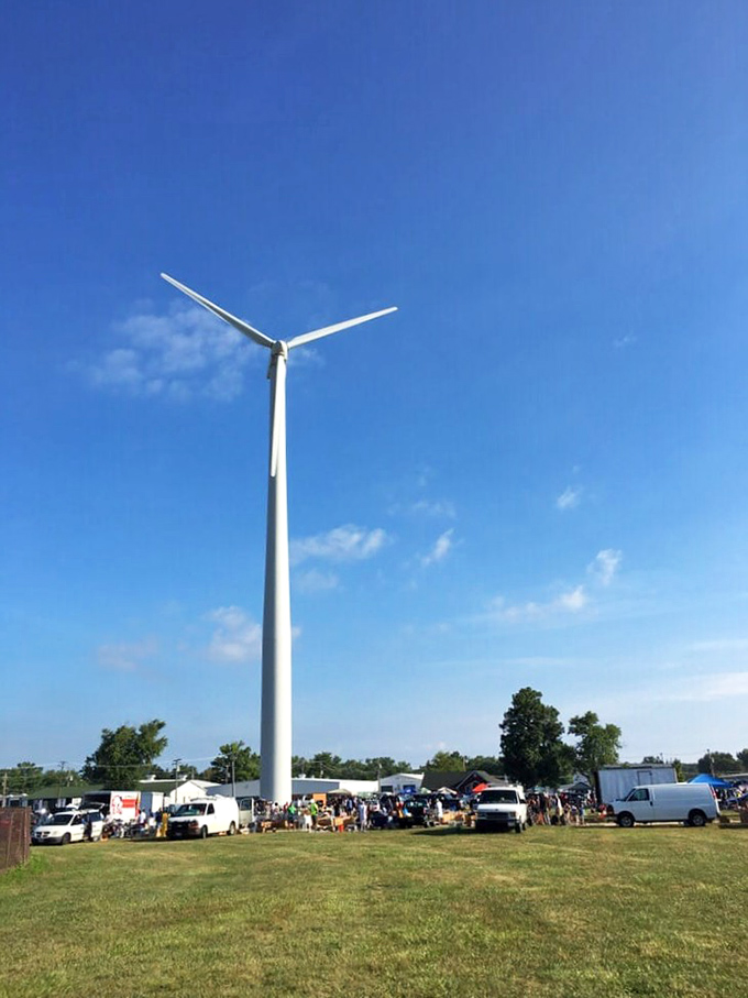 The market's guardian windmill stands tall against blue skies, watching over vendors and visitors alike in this weekend ritual of commerce.