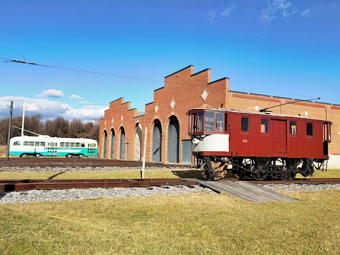 Historical trolleys frame the distinctive stepped roofline of the museum's car barn. These tracks lead to preservation rather than downtown destinations now.