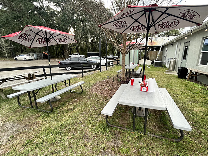 Picnic tables where memories are made between bites. The Dr. Pepper umbrellas understand that good barbecue deserves good shade.