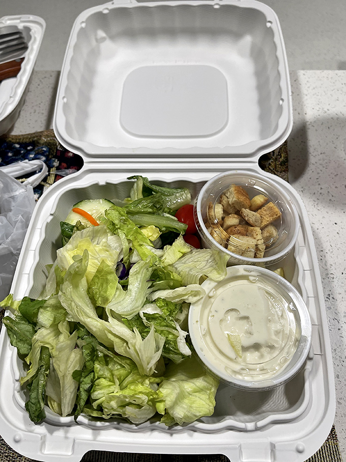 Even the side salad gets special attention—fresh greens, crisp vegetables, and house-made dressing in a to-go container for road trip munching.