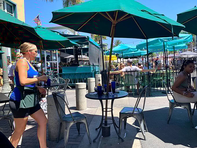 The outdoor patio buzzes with the energy of beach-goers fueling up for the day. Those green umbrellas provide shade for what might be the most important meal decision of your vacation.