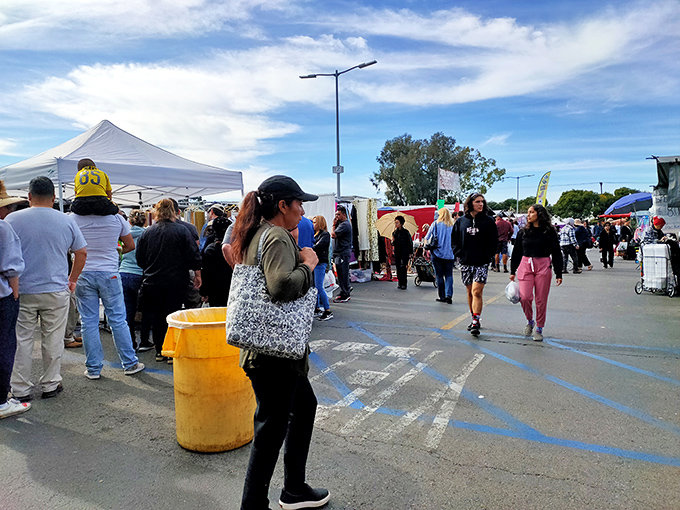 The weekend market social club in session. Shoppers of all ages navigate this asphalt bazaar, united in the universal language of treasure hunting.