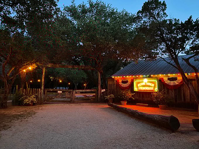 The rustic entrance to Perini Ranch glows at dusk, promising a Texas-sized welcome and mesquite-grilled perfection beyond those gates.