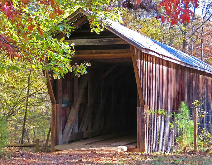 Fall foliage creates nature's perfect backdrop for this historic wooden passage. Like walking through a painting that creaks beneath your feet!
