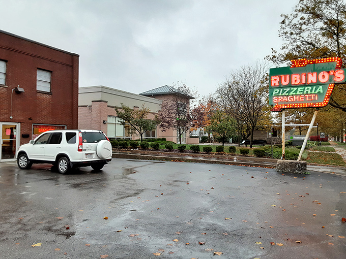 That classic neon sign promises pizza perfection, and those red-checkered curtains whisper of old-school Italian tradition.