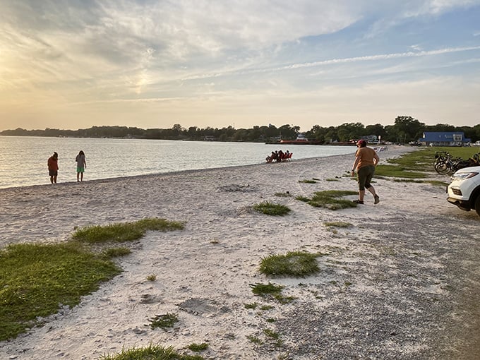 Golden hour transforms this humble shoreline into a painter's dream. Visitors stroll along the water's edge, collecting memories with each step.