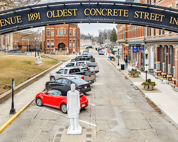A white statue stands sentinel on America's oldest concrete street, where modern cars park on 130-year-old innovation.