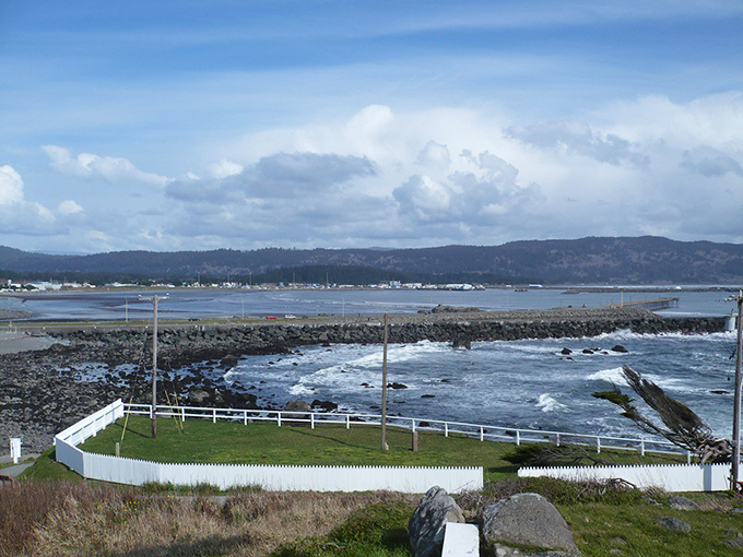 The harbor's protective embrace shelters fishing boats while mountains stand guard in the distance – nature's version of a perfect security system.
