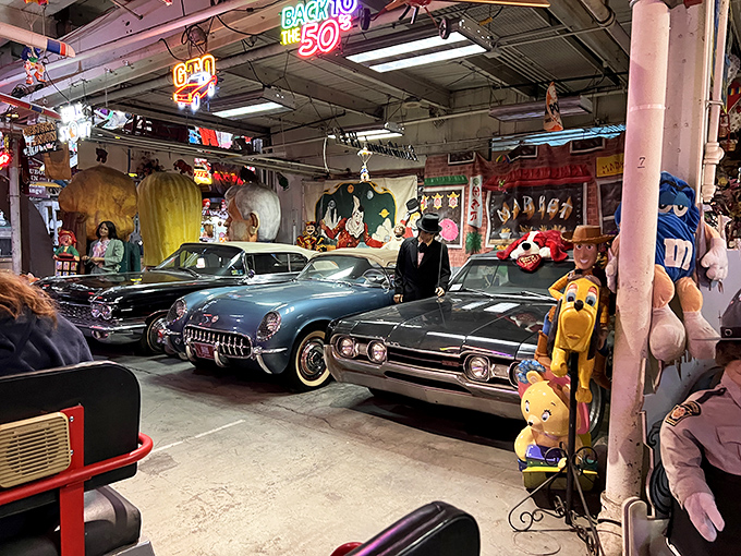 Detroit's finest chrome beauties rest among cartoon companions, like a fever dream where classic cars and childhood icons decided to throw a party together.