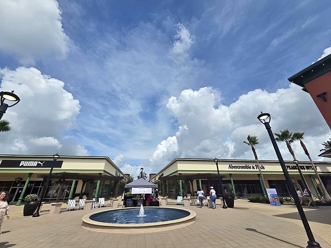 Blue skies frame the outdoor shopping paradise where Puma meets Abercrombie & Fitch, with a serene fountain offering respite for weary shopping warriors.