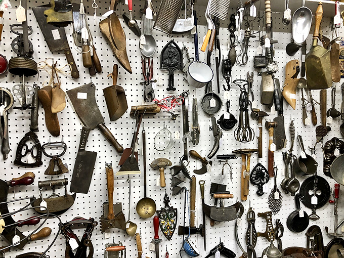 Kitchen implements with stories to tell. Each wooden handle and metal edge represents someone's daily life from decades past&mdash;practical poetry hanging on pegboard.