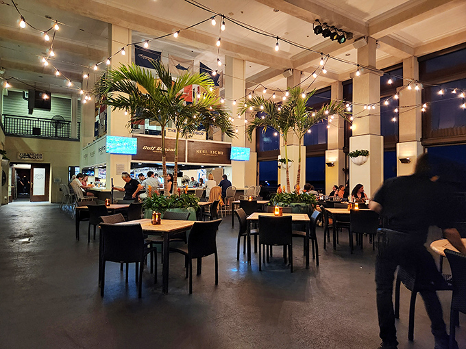 Soaring ceilings, string lights, and strategically placed palms create an atmosphere that whispers "upscale" while still letting you wear your favorite vacation shirt.