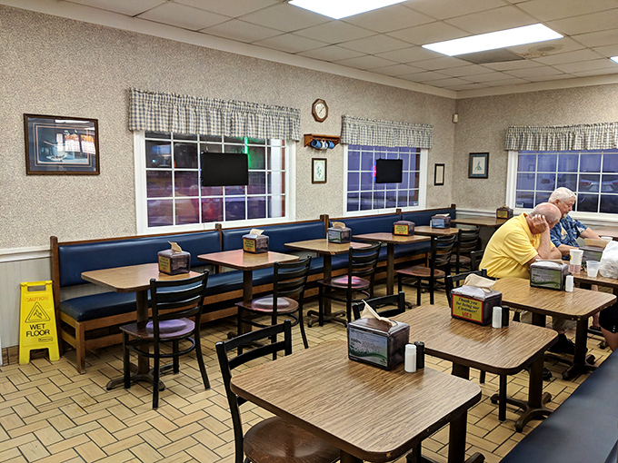 Checkered curtains and blue bench seating create that "grandma's kitchen" vibe where calories don't count and conversations flow as freely as the sweet tea.