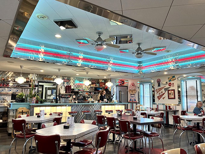 Neon ceiling strips cast that unmistakable retro glow, while chrome and vinyl create the perfect backdrop for making memories over milkshakes.