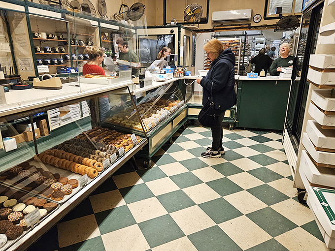 The classic checkered floor and glass display cases create a time capsule of American donut culture. Sweet treasures await behind that glass.