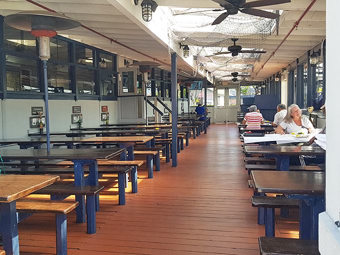 Nautical charm meets practical dining along this wooden walkway. The fishing nets overhead aren't just decoration&mdash;they're setting the perfect mood.