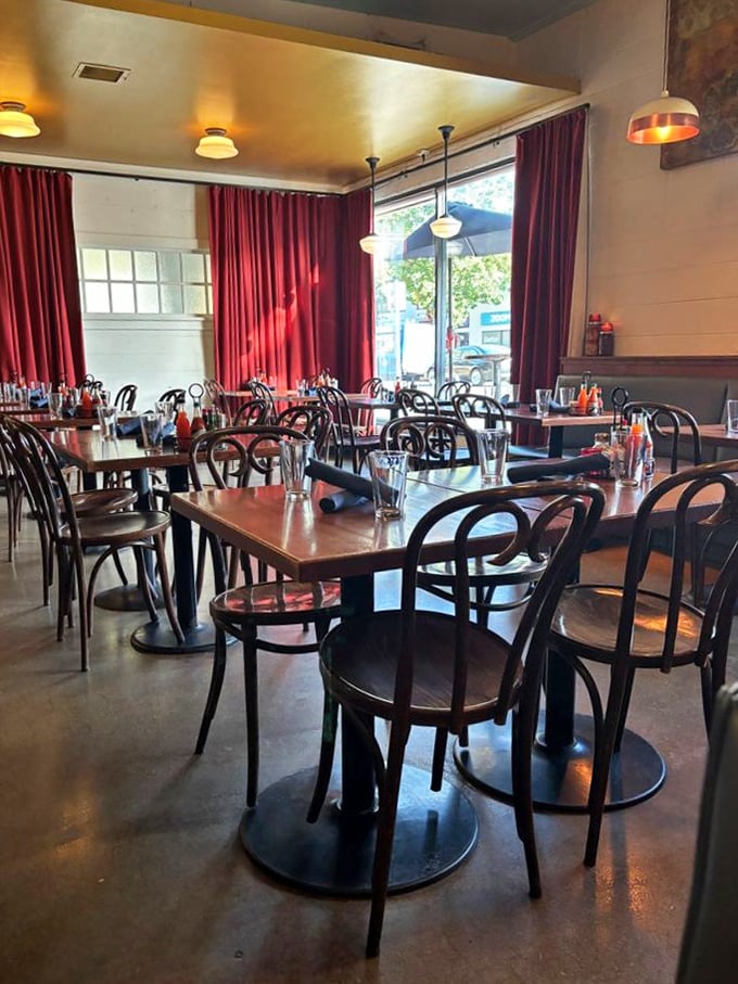 Rich red curtains frame the dining room, where bistro chairs await hungry patrons. Simplicity never looked so inviting.
