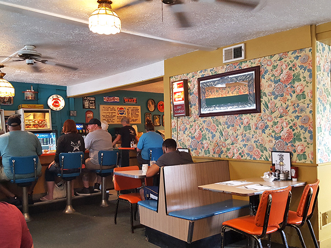Inside, the classic diner aesthetic comes alive with floral wallpaper, vintage fixtures, and those iconic blue counter stools where breakfast dreams come true.