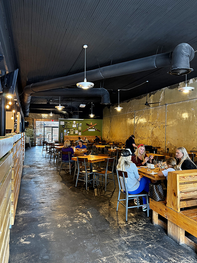 Industrial-chic meets cozy comfort inside, where gold-toned walls and exposed ductwork create the perfect backdrop for brunch-time conversations that flow as easily as the coffee.