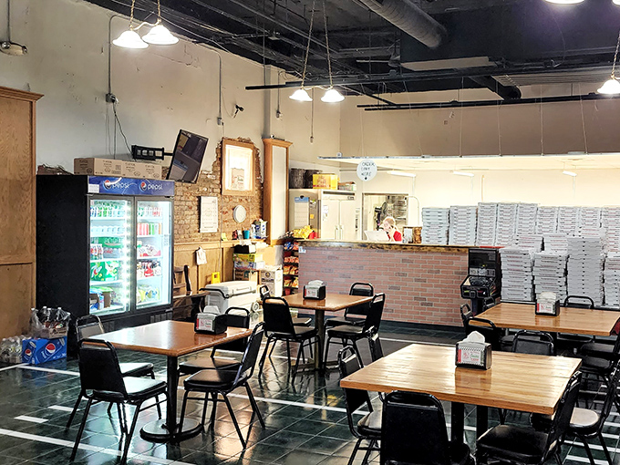 No-frills dining at its finest&mdash;simple tables, practical chairs, and stacks of pizza boxes standing ready for their noble mission.