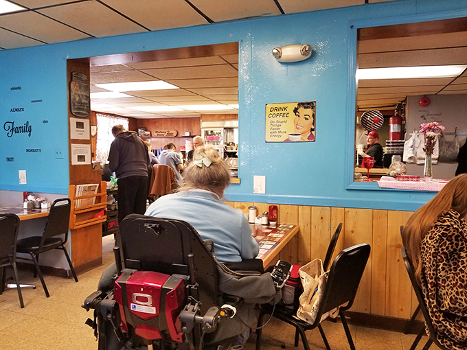 Blue walls and wood paneling create the perfect backdrop for morning conversations, while that vintage coffee sign speaks the absolute truth.