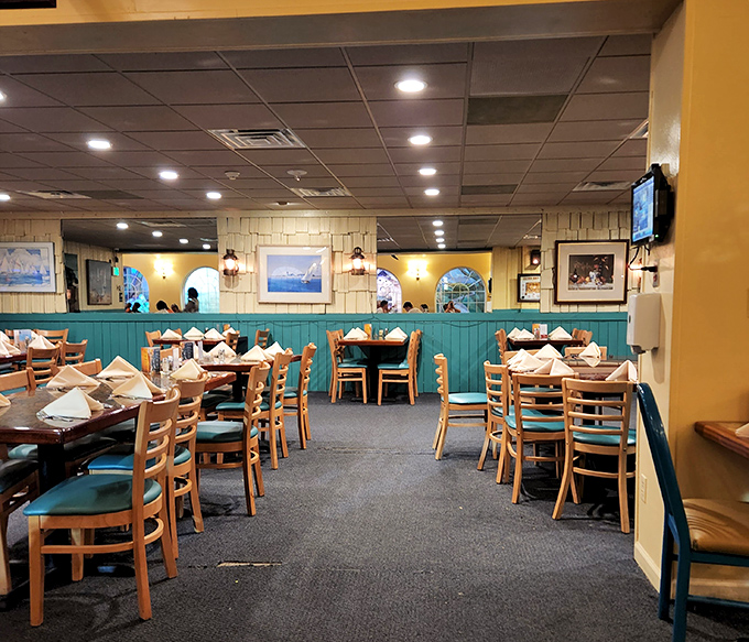 Turquoise wainscoting meets maritime charm in this dining room where every table setting awaits its next seafood enthusiast. The napkins stand at attention like tiny sailboats.