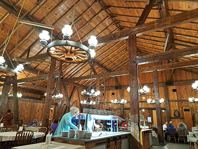 Cathedral-like wooden beams soar overhead while wagon wheel chandeliers cast a warm glow. Dining here feels like stepping into a Norman Rockwell painting.