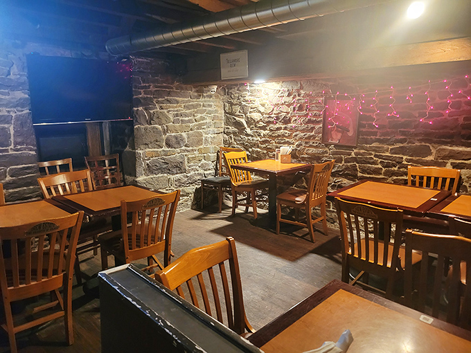 Stone walls that have witnessed a century of stories now frame intimate dining spaces. The warm glow of string lights transforms this historic space into a cozy culinary haven.