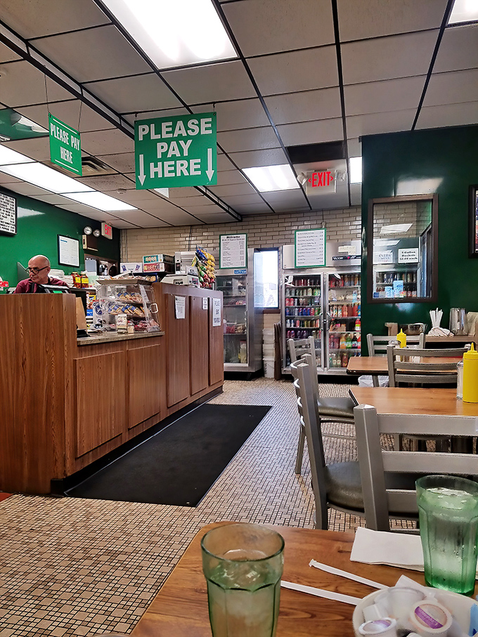 No fancy frills here—just the essentials: a counter where sandwich magic happens, simple tables, and those distinctive green glasses that scream "authentic deli."